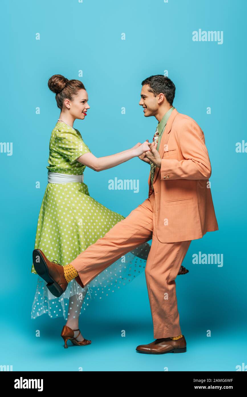side view of stylish dancers holding hands while dancing boogie-woogie ...