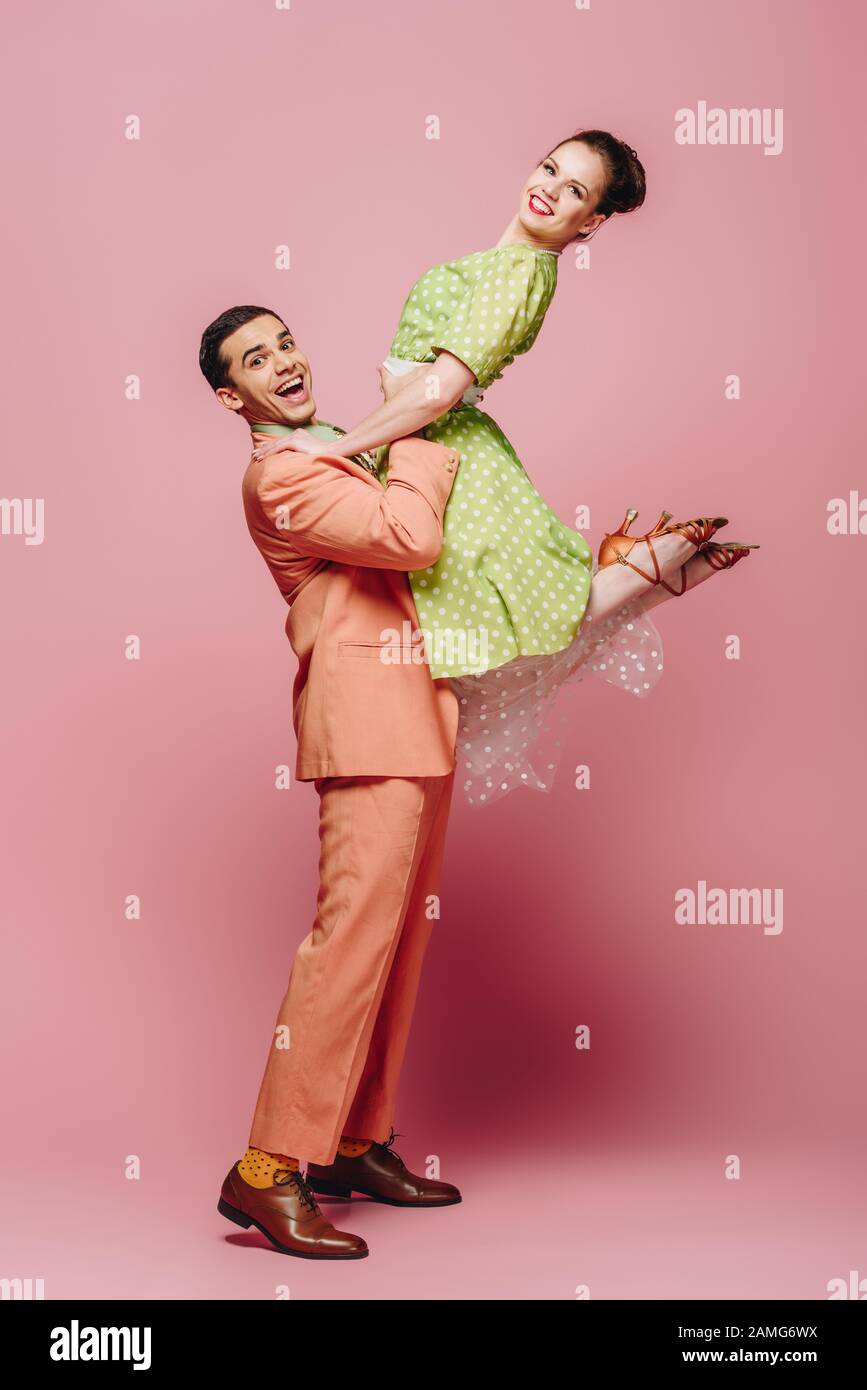 stylish dancer holding girl while dancing boogie-woogie on pink ...