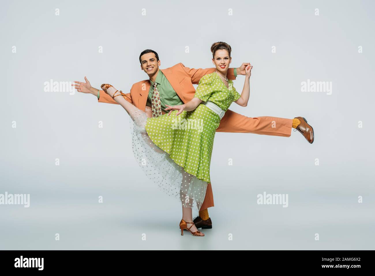 happy dancers looking at camera while dancing boogie-woogie on grey ...