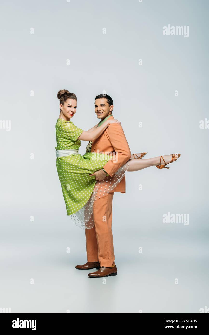 stylish dancer holding girl while dancing boogie-woogie on grey ...