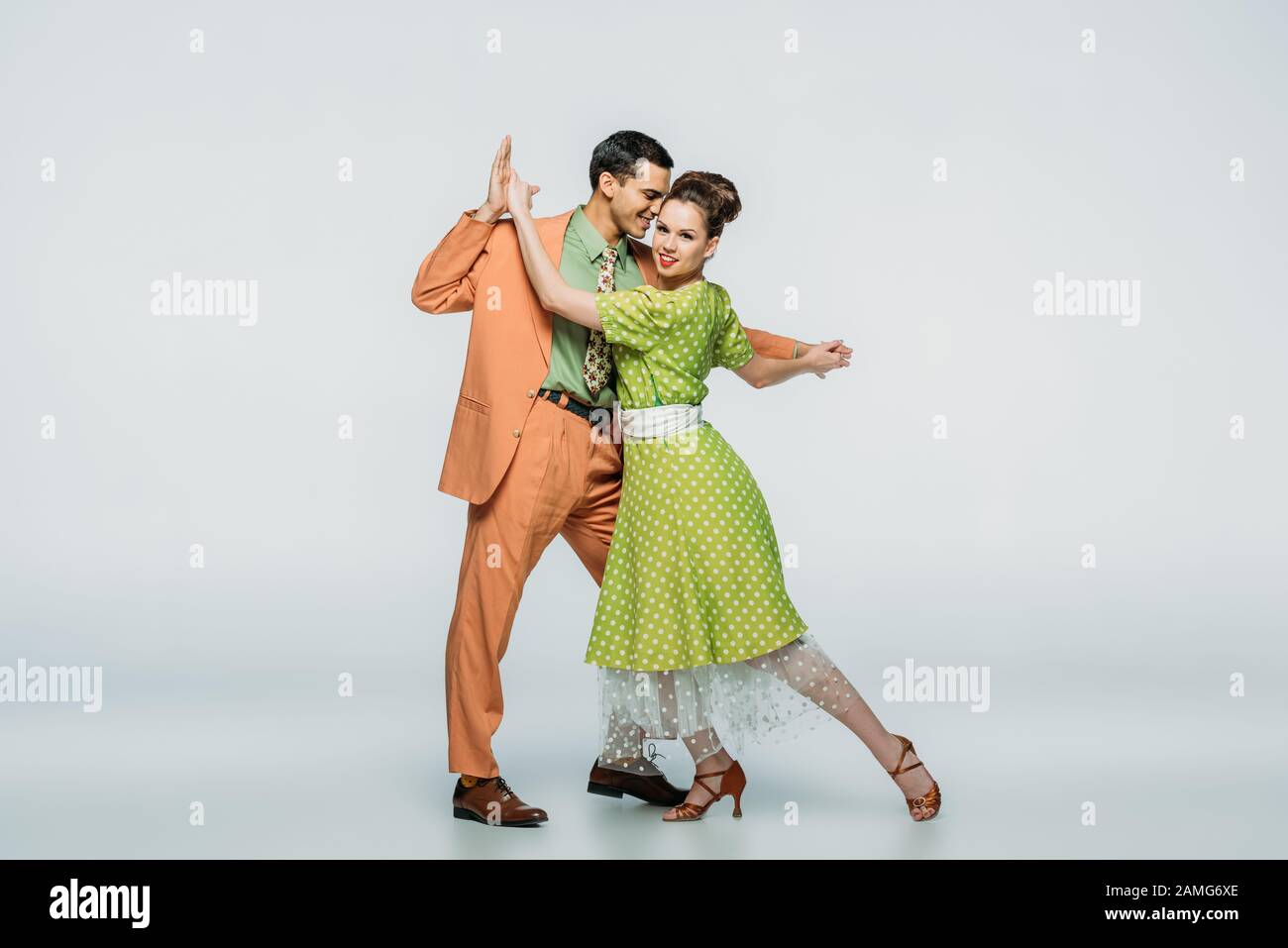 stylish dancers holding hands while dancing boogie-woogie on grey ...