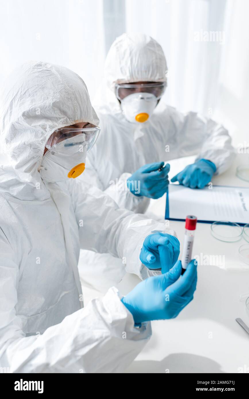 selective focus of multicultural scientists pointing with finger at dna ...
