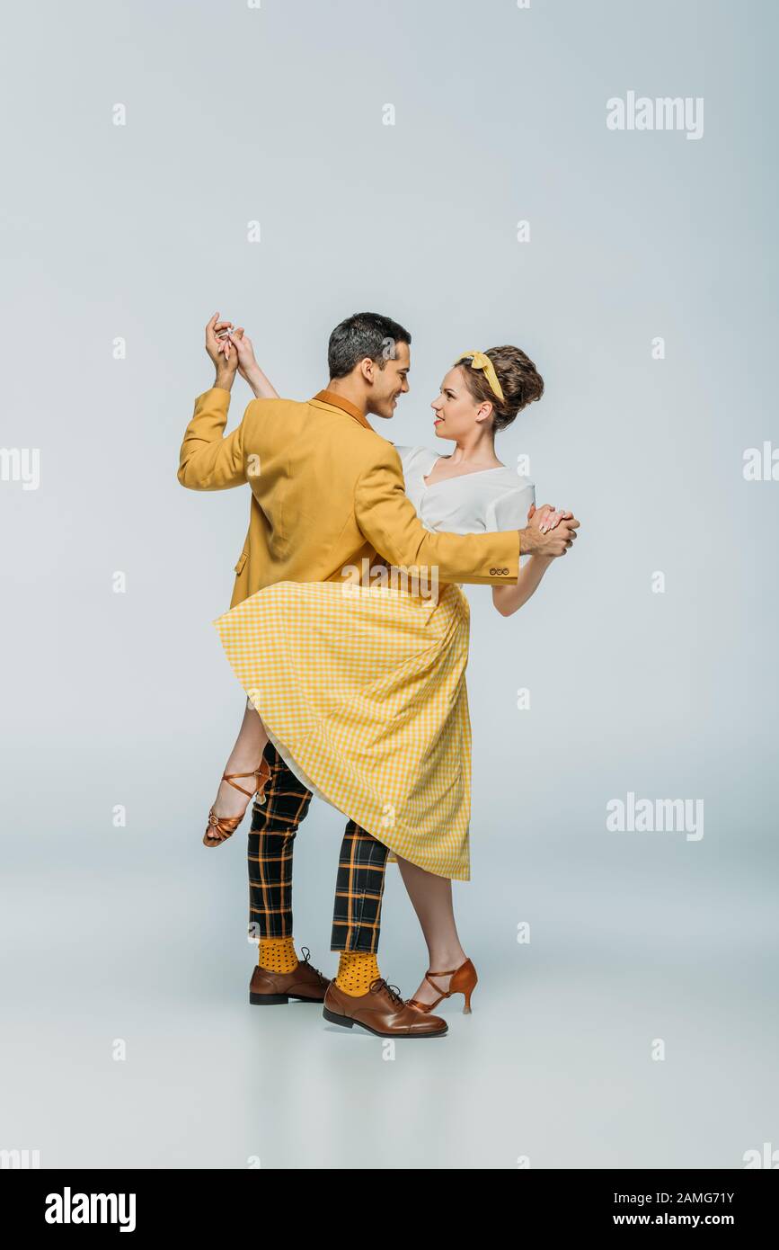 elegant dancers holding hands while dancing boogie-woogie on grey ...