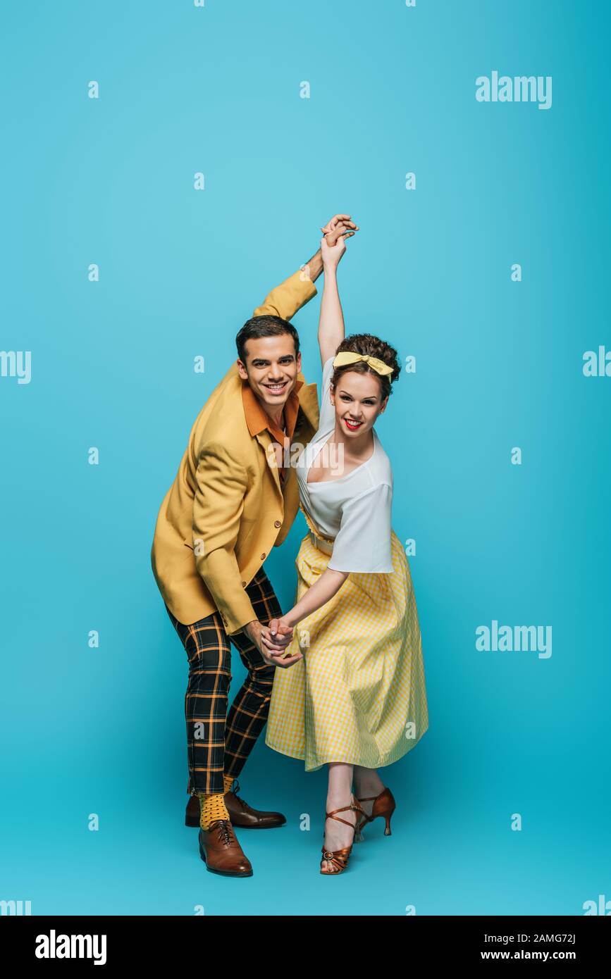 stylish dancers holding hands while dancing boogie-woogie on blue ...