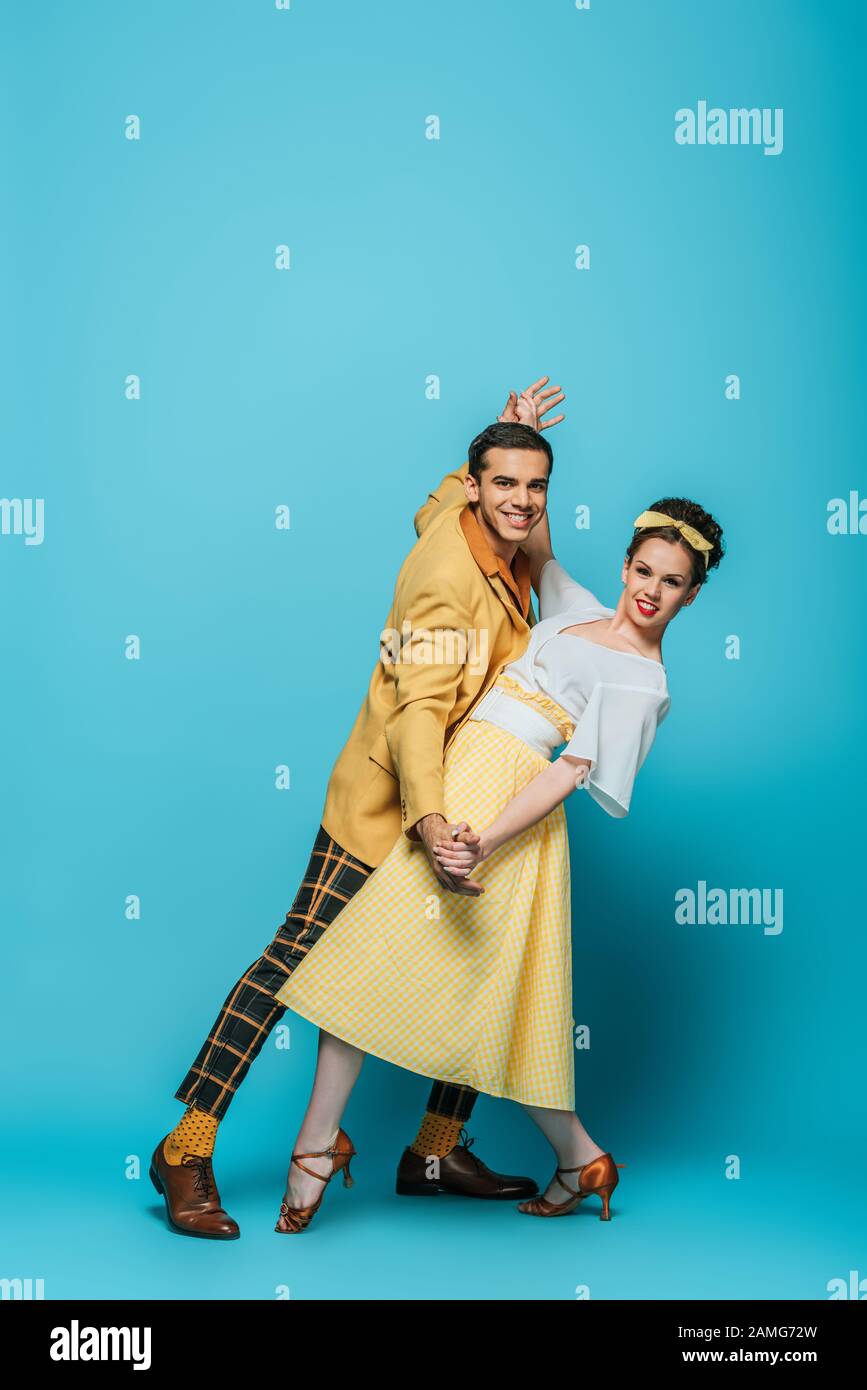 stylish dancers holding hands while dancing boogie-woogie on blue ...