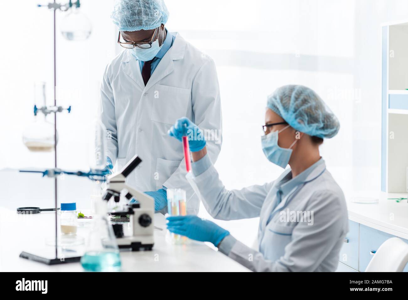 multicultural biologists in white coats doing test in lab Stock Photo ...