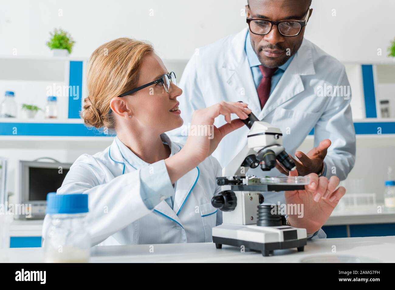 multicultural biologists in glasses looking at microscope in lab Stock ...