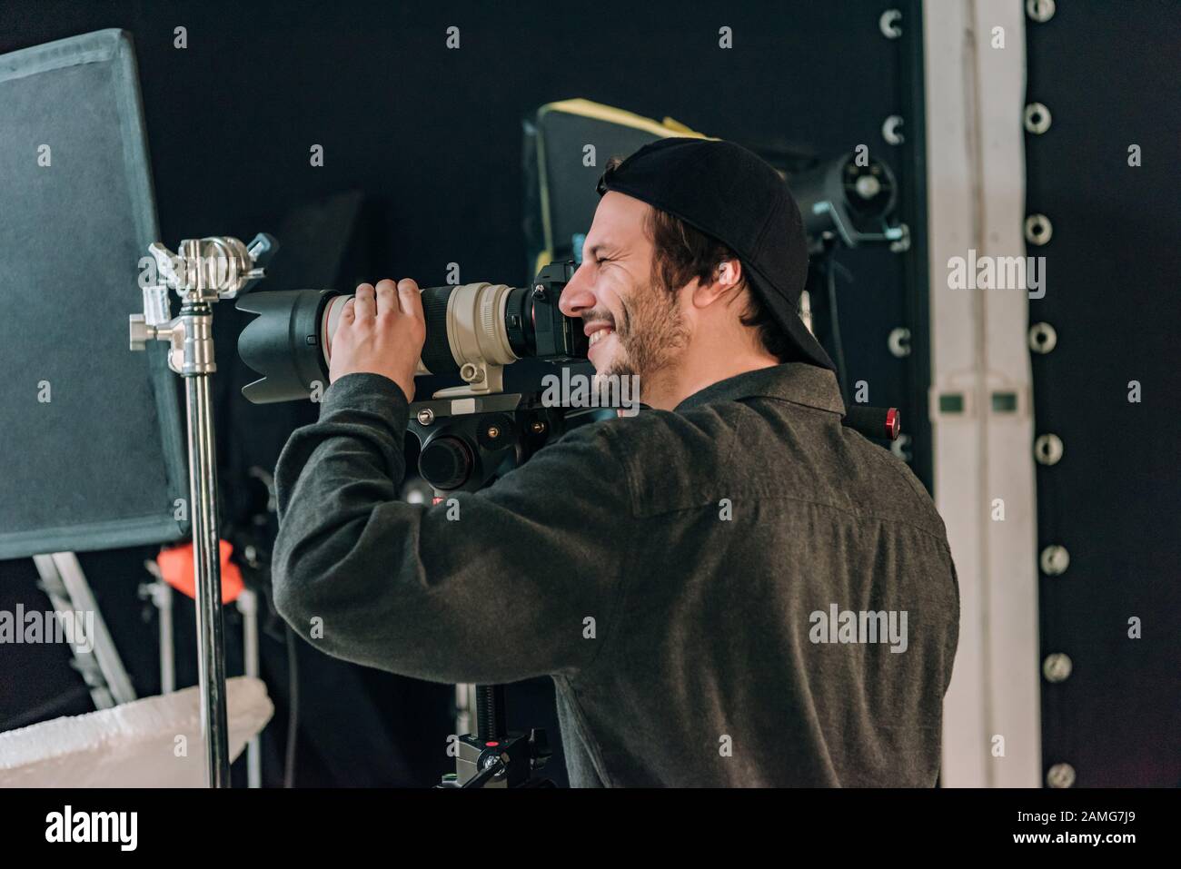 Side view of smiling handsome cameraman working in photo studio Stock ...