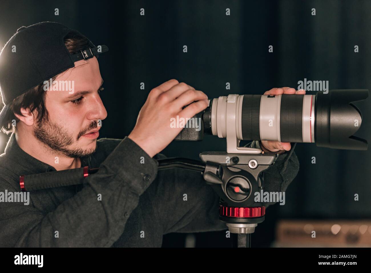 Side view of videographer looking at camera display while working in ...