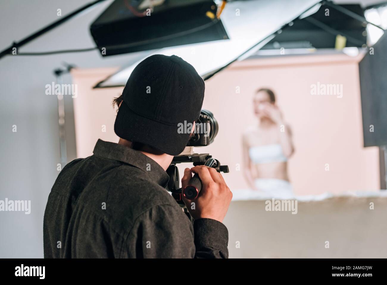Back view of cameraman working with female model in photo studio Stock ...