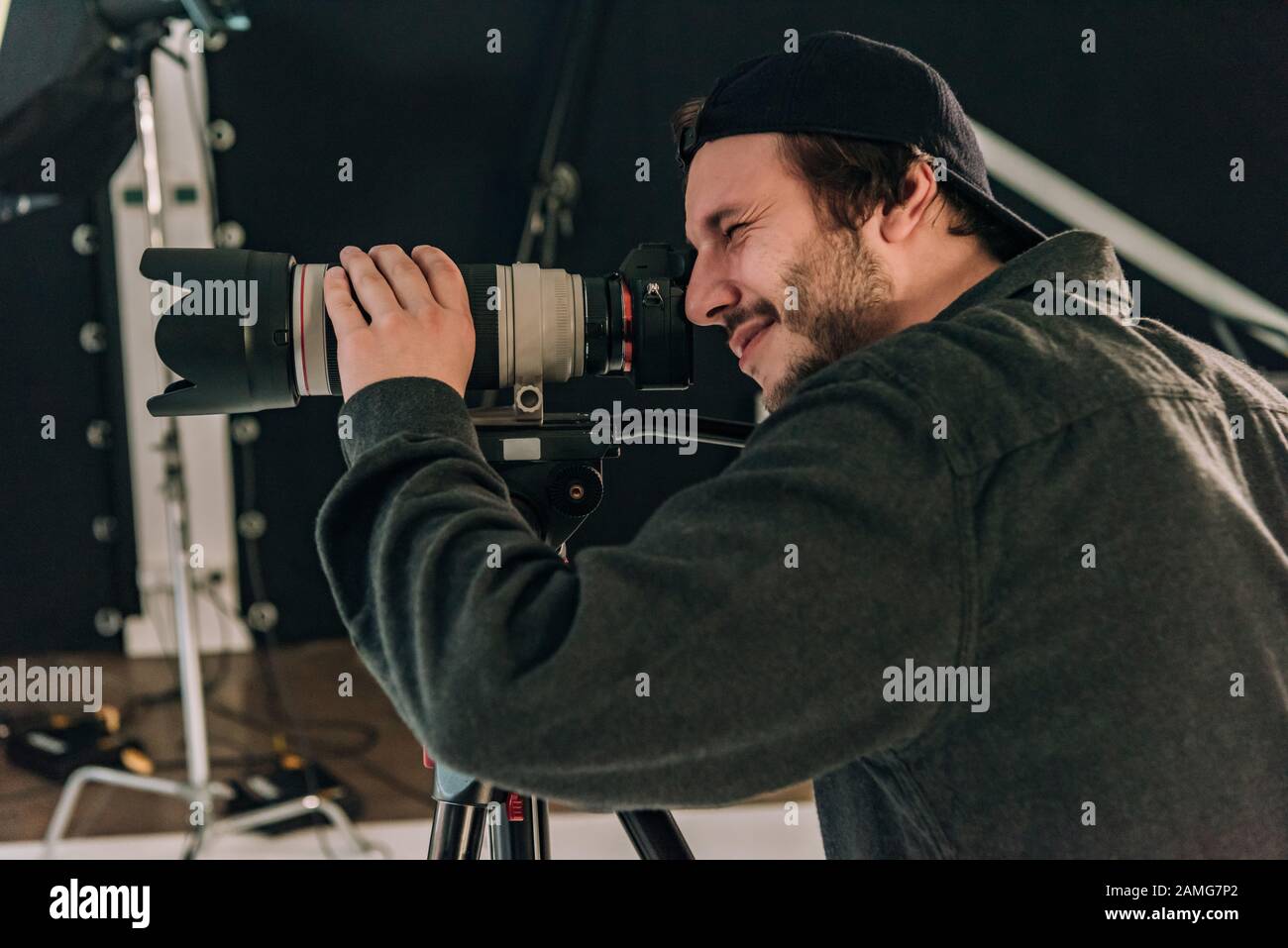 Side view of smiling cameraman with camera at workplace Stock Photo - Alamy