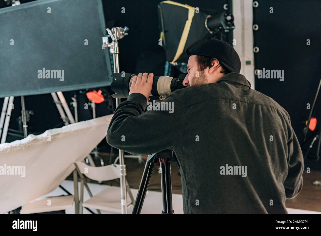 Side view of videographer with camera and reflectors at background ...