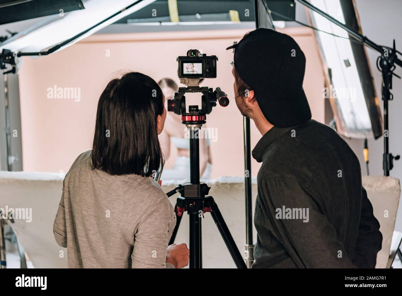 Rear view of cameraman and assistant looking at camera display while ...