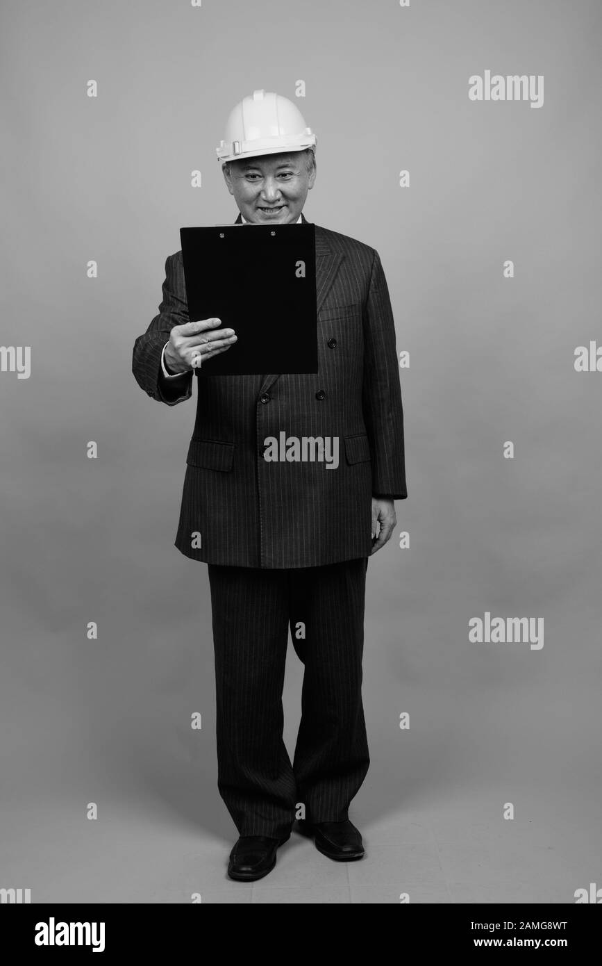 Studio shot of mature Asian businessman as engineer with hardhat ...