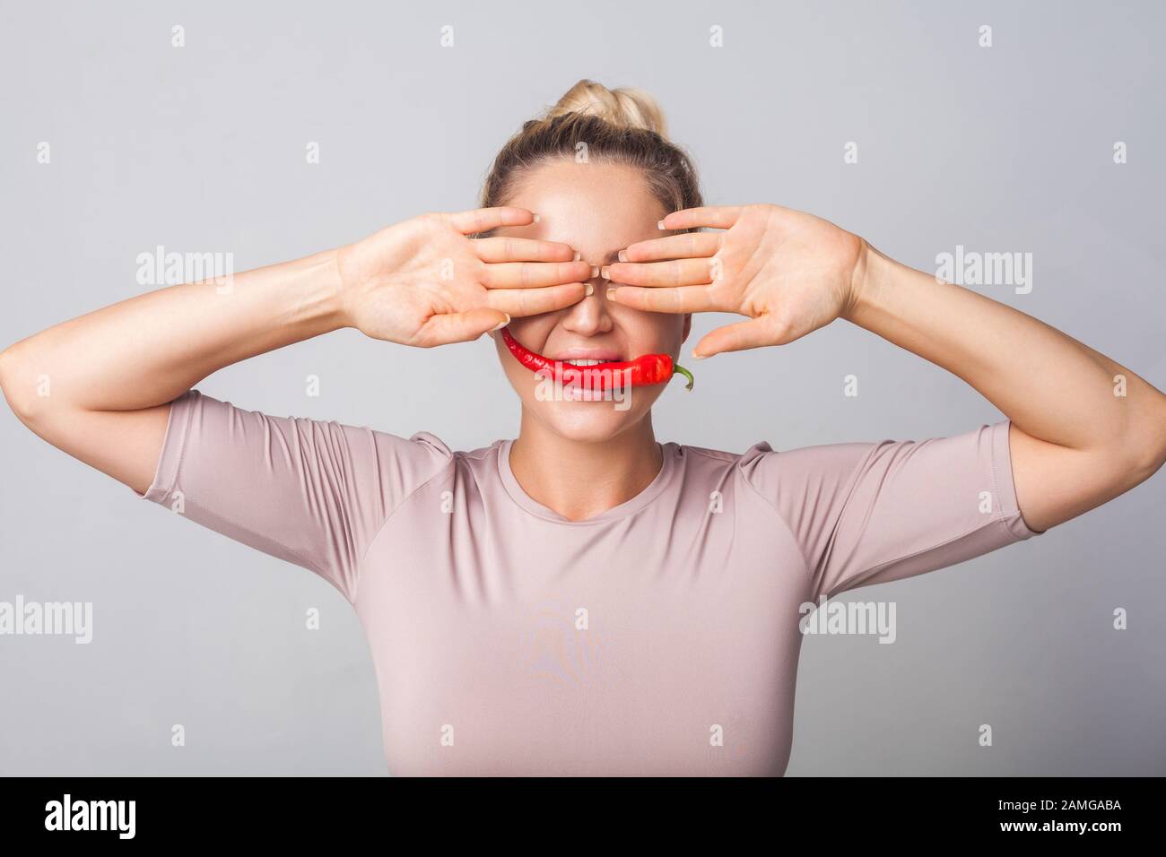 Portrait of young cute woman covering eyes with hands and biting red ...