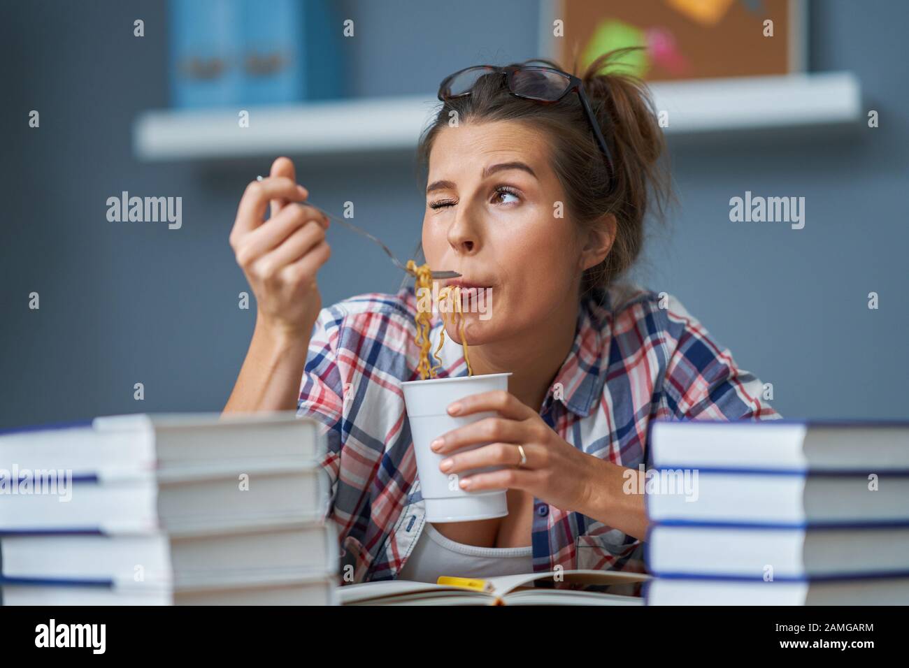 Hungry student eating noodle while learning at home Stock Photo - Alamy