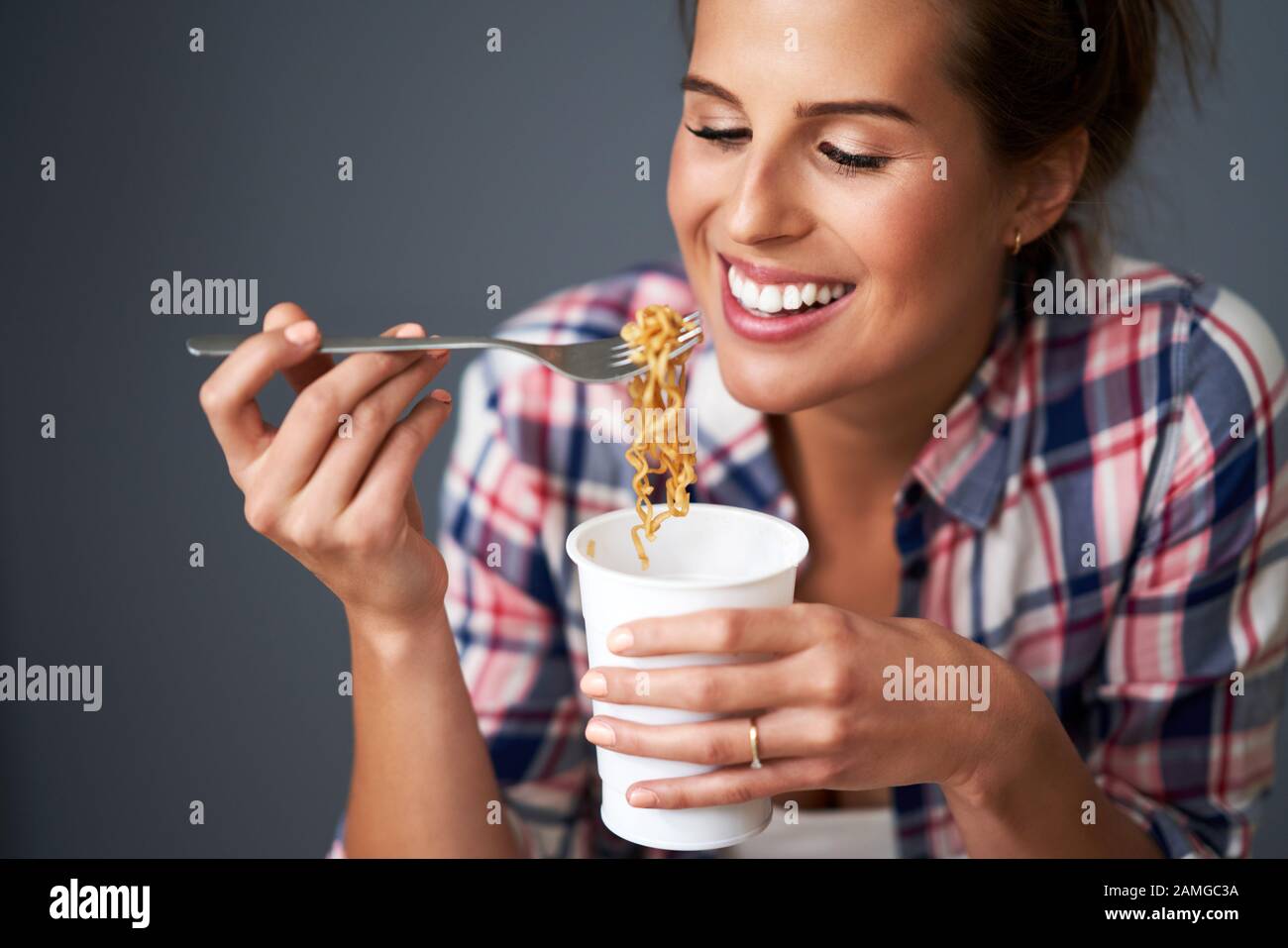 Hungry student eating noodle while learning at home Stock Photo - Alamy