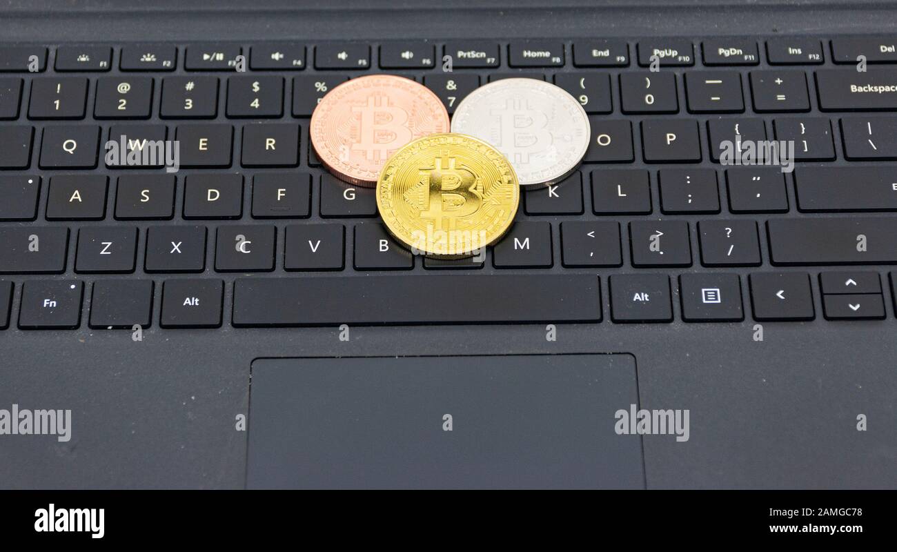 Three botcoin coins on top of a black computer keyboard with white ...