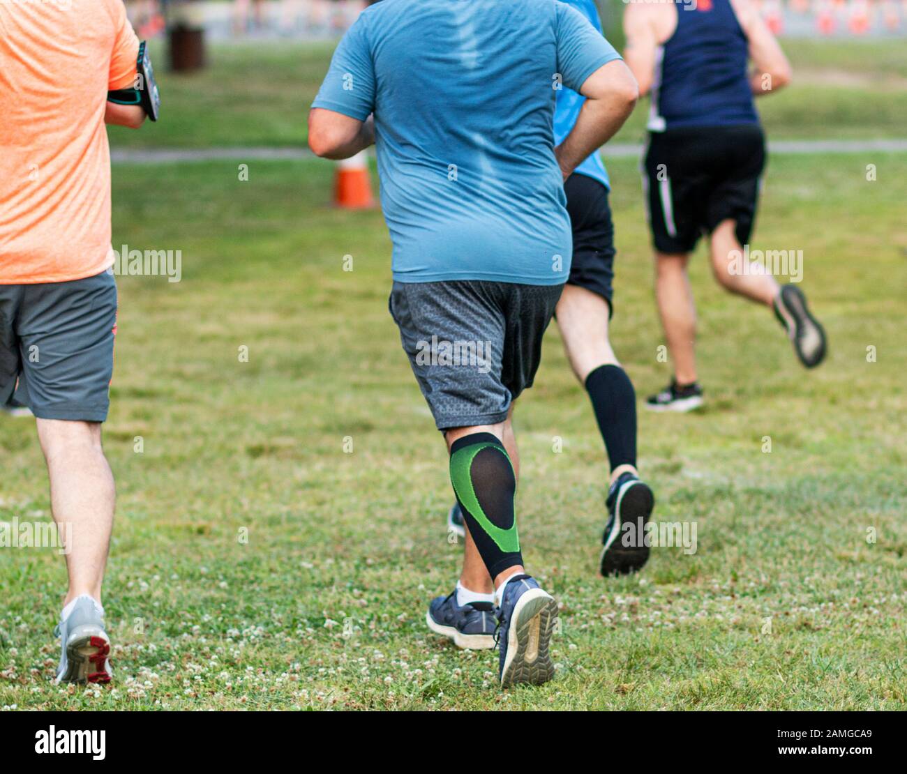 Rear view of a runner with a black and green compression calf sleeve ...