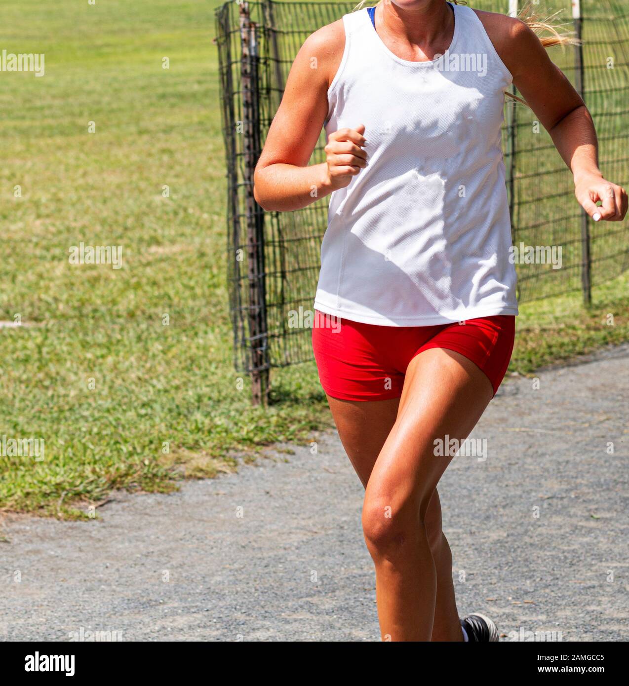 A high school girls is running in a cross country race down the final ...