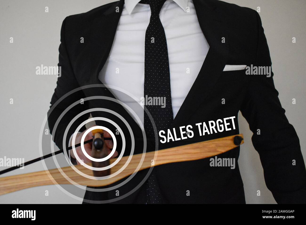 A close up view of a business man in a suit holding a wooden crossbow ...