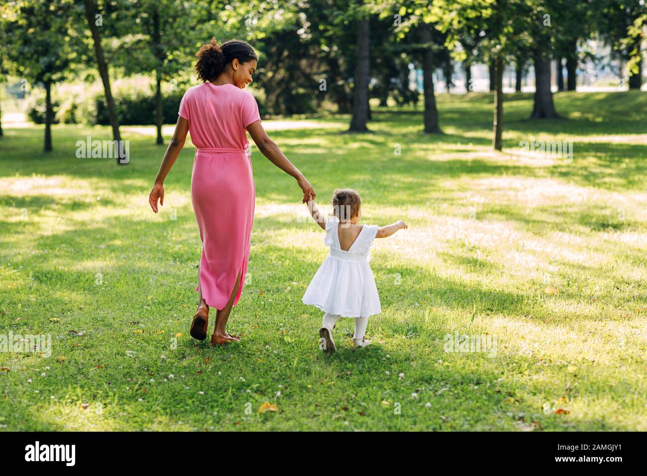 Back view of mother and daughter running hand in hand in a park Stock ...