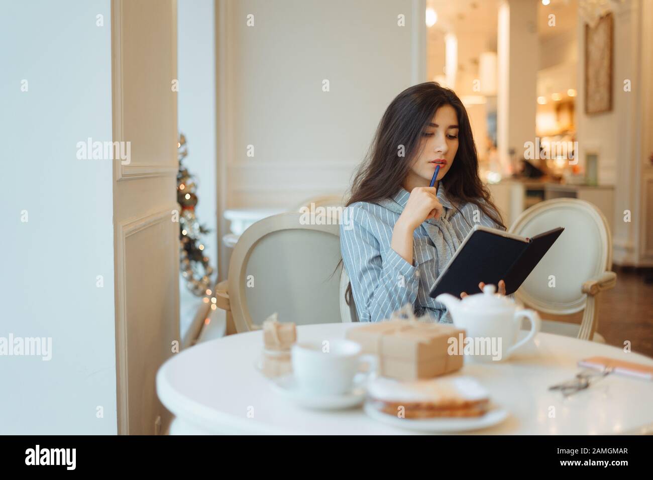 Thoughtful young woman holding notepad and thinking on creative ideas ...