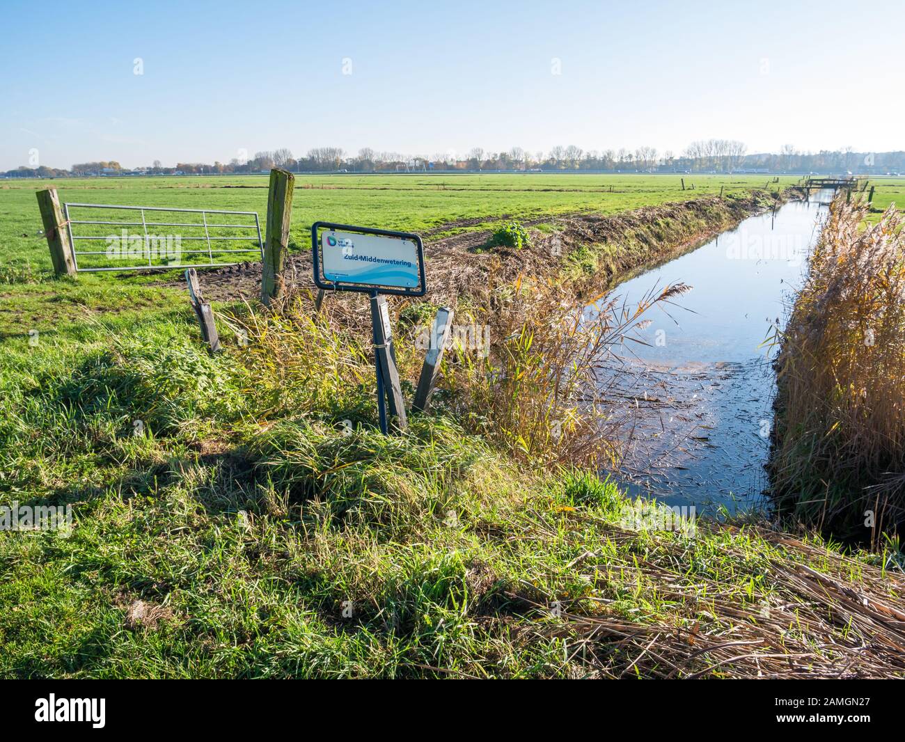 Drainage ditch and open gate leading on to meadow in polder Eempolder ...