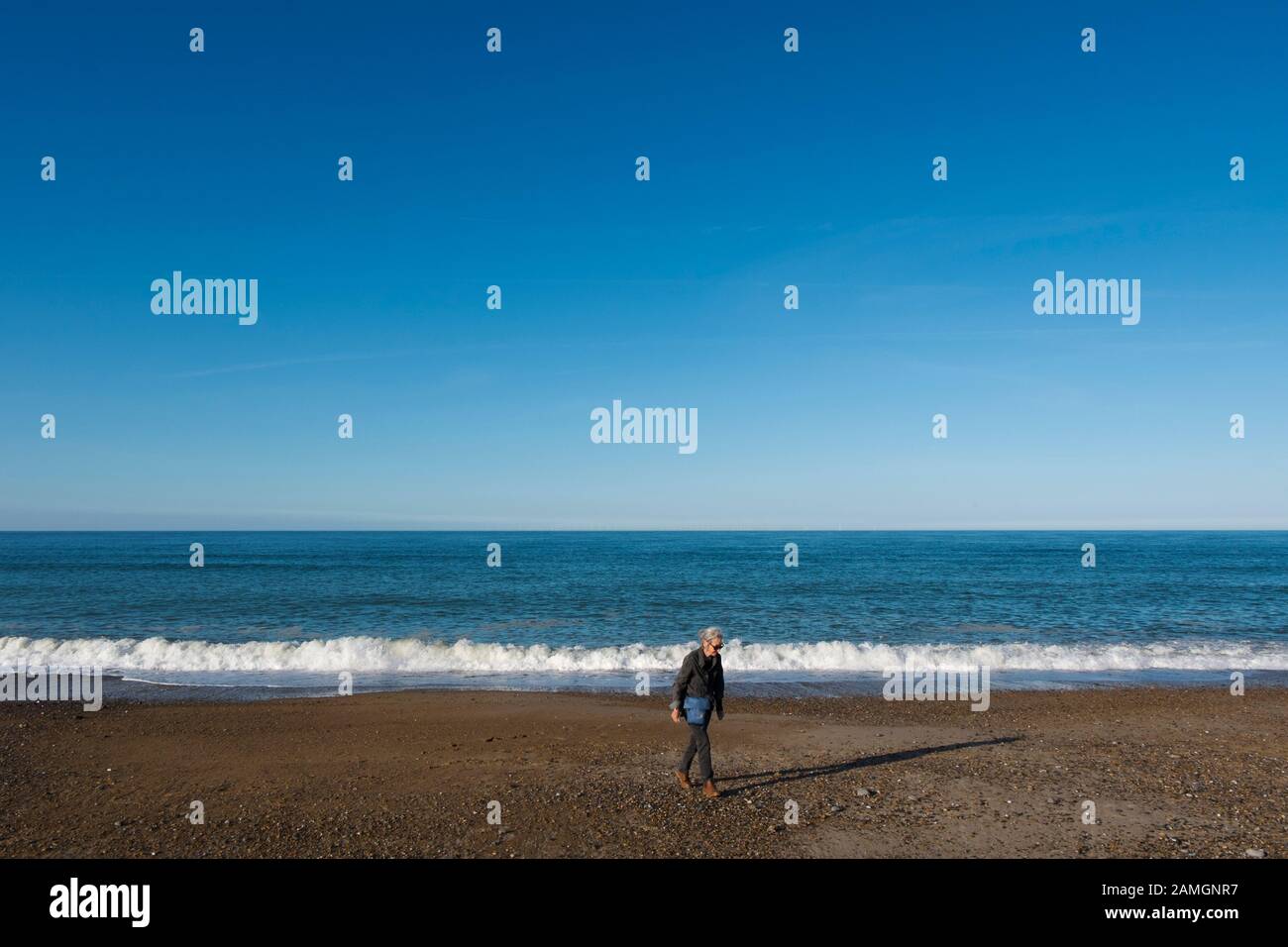 A woman beachcombing on the beach at Cley Next The Sea, North Norfolk ...