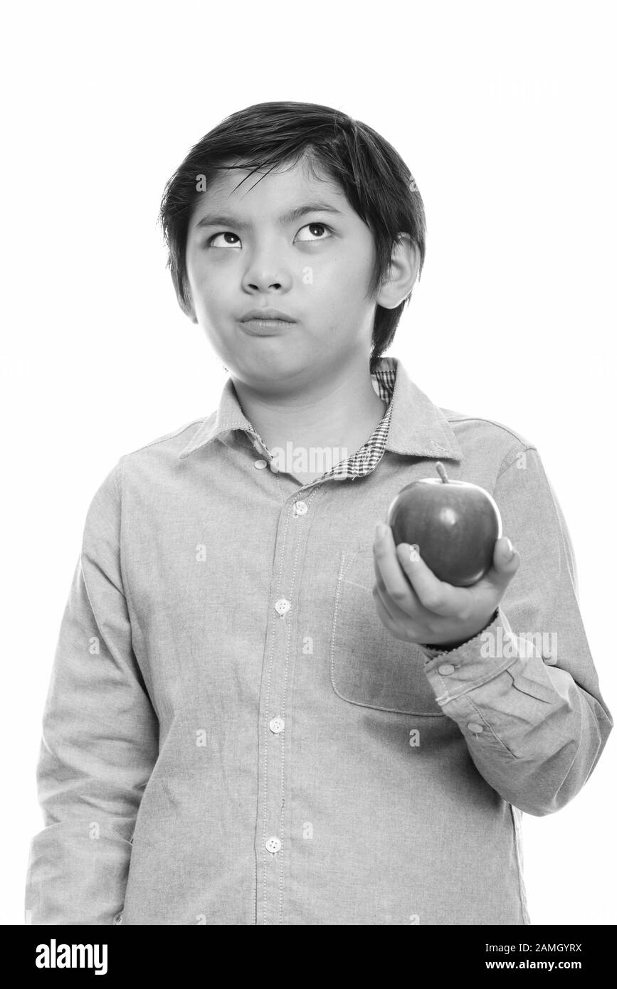 Studio shot of cute Japanese boy holding red apple while thinking Stock ...