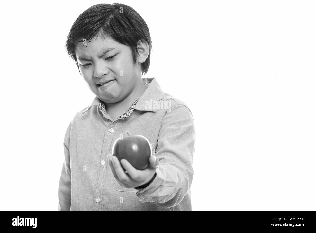 Studio shot of cute Japanese boy holding red apple and looking ...