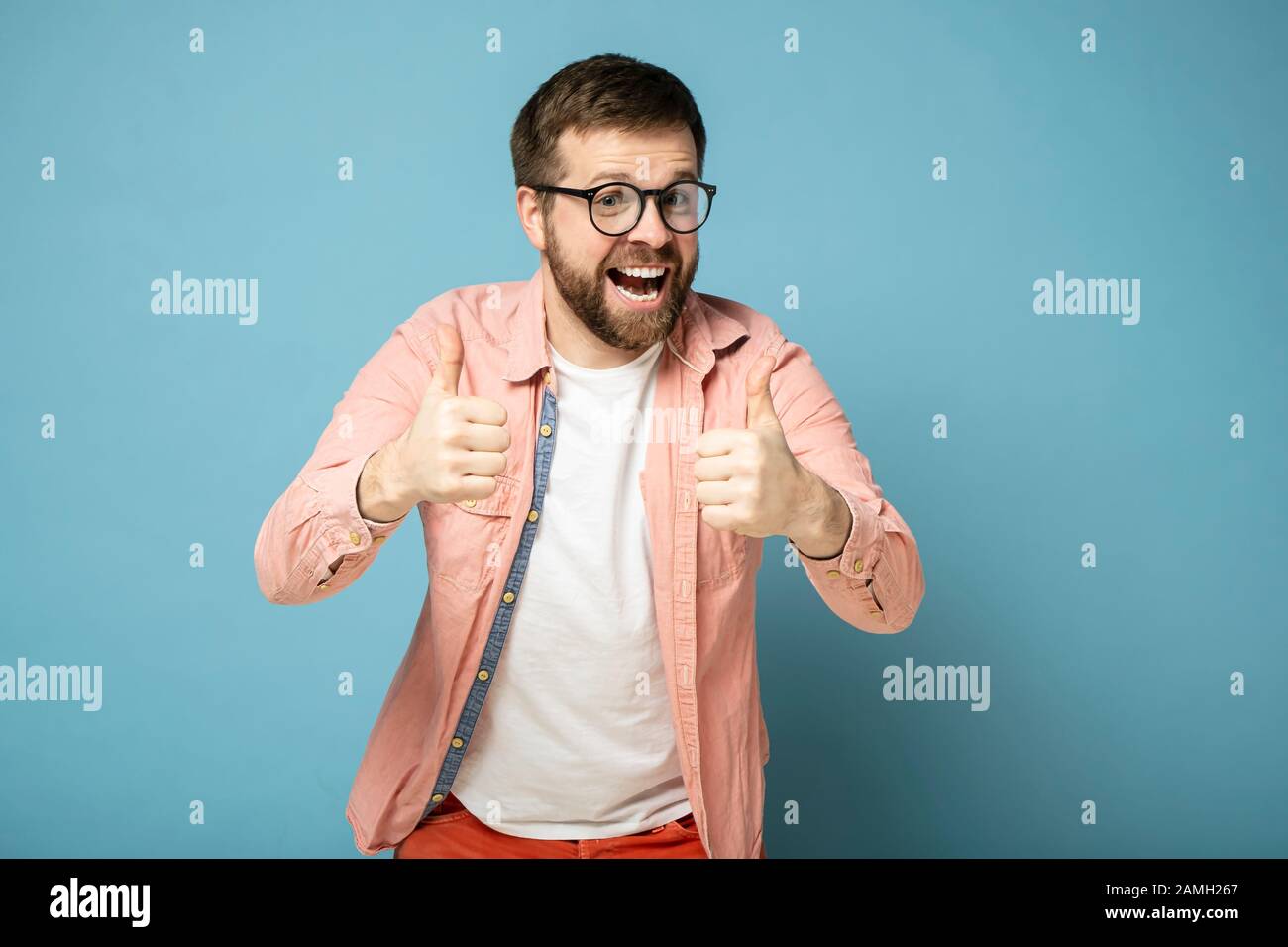 Positive bearded man makes a approving gesture with hands, thumbs up ...