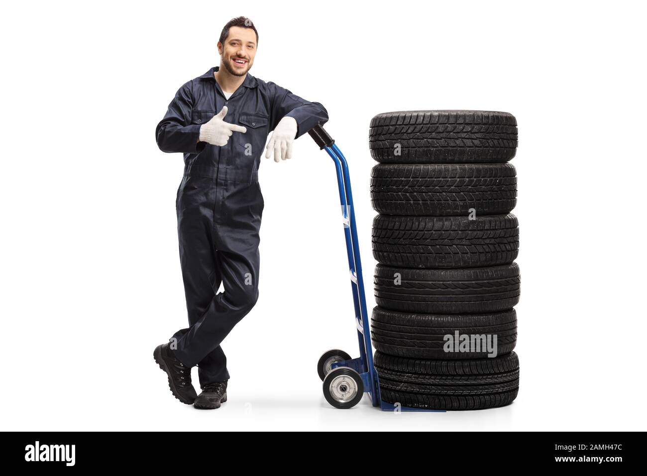 Full length portrait of an auto mechanic pointing to a hand truck with ...