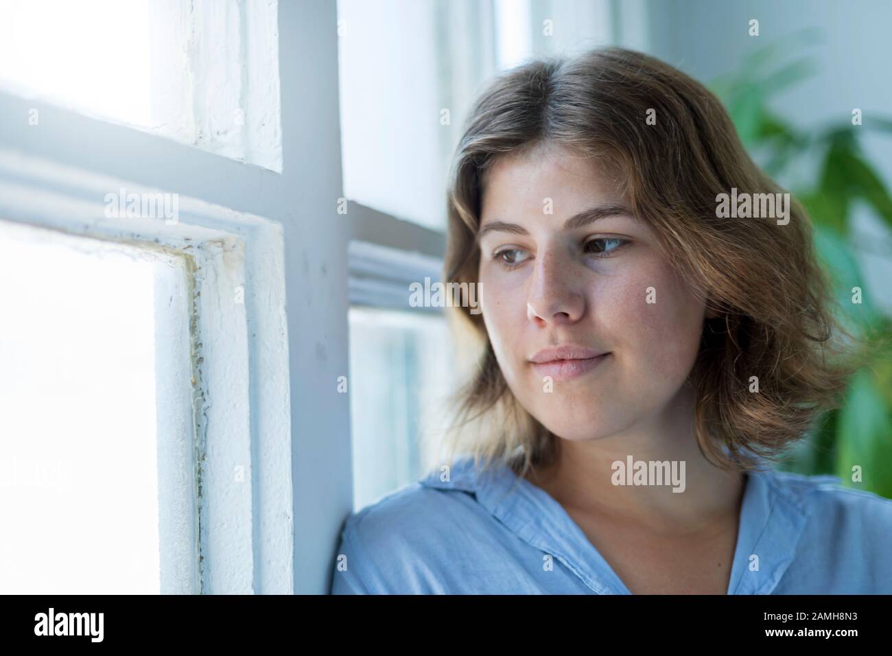 Woman leaning on a window, looking out of window Stock Photo - Alamy