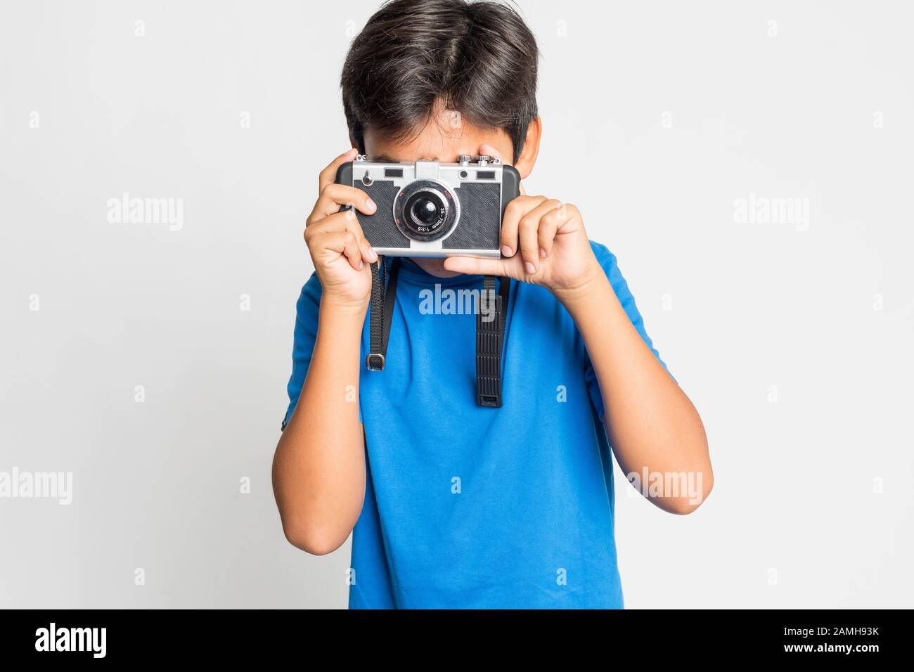 Portrait of a cute young boy with camera isolated on white background ...