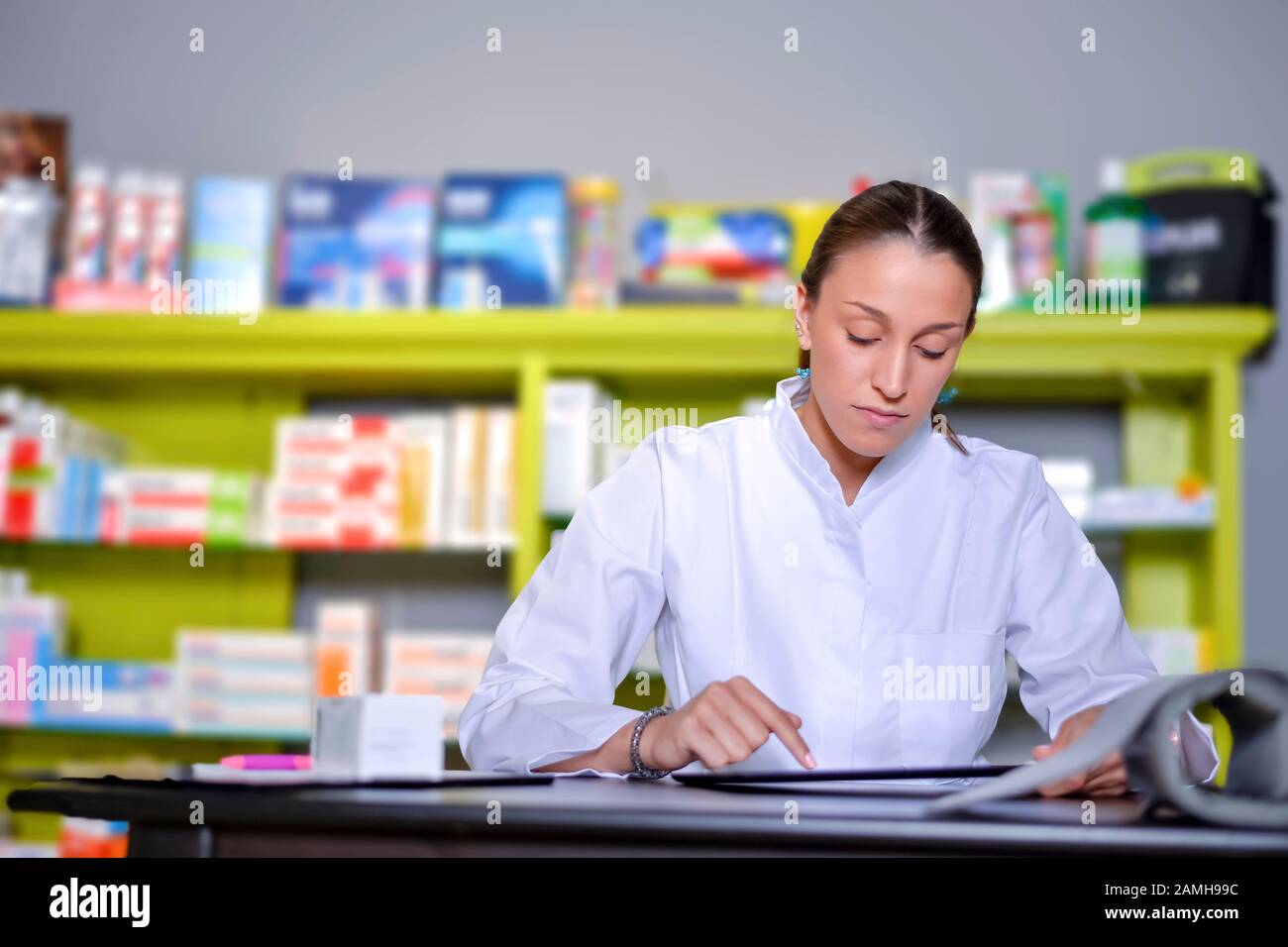 Smiling happy confident young woman pharmacist working on a desk in the ...