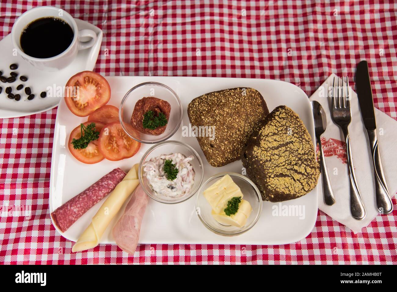 on a red chequered tablecloth is a plate with a hearty breakfast and a ...