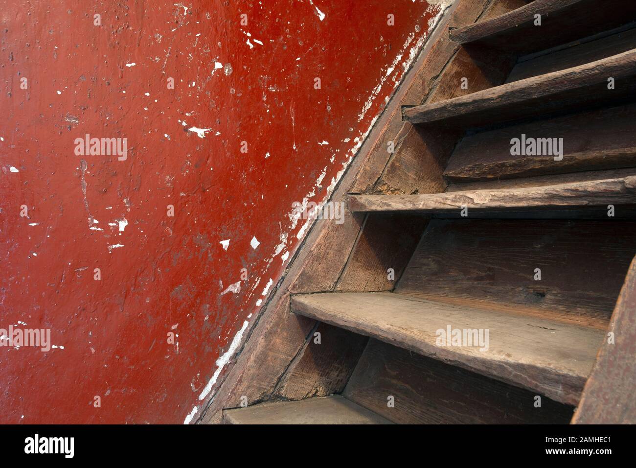 Old damaged brown wooden stairs and red wall leading to the attic ...
