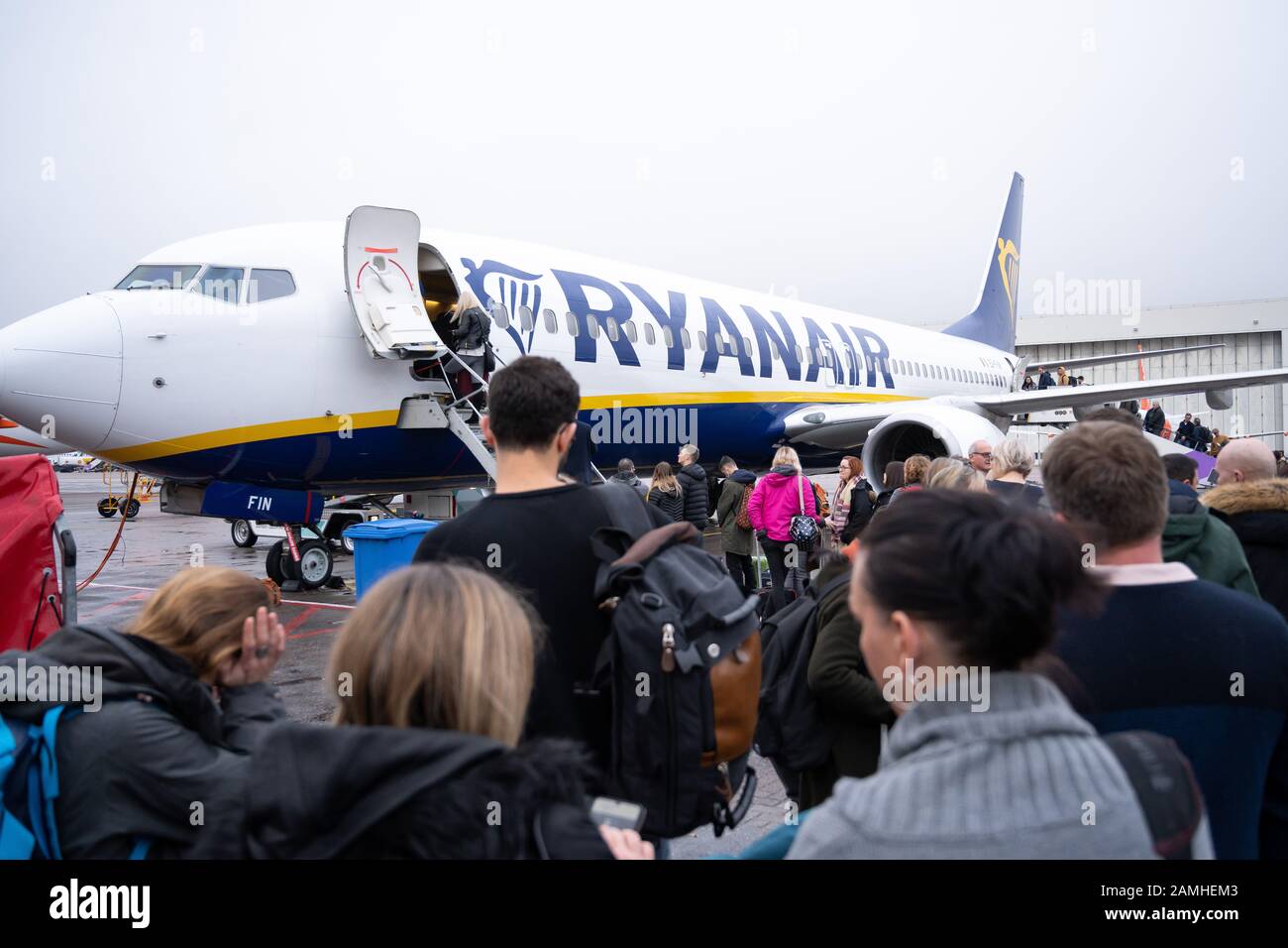 Passengers queue to board a RyanAir flight at Luton airport in Luton ...