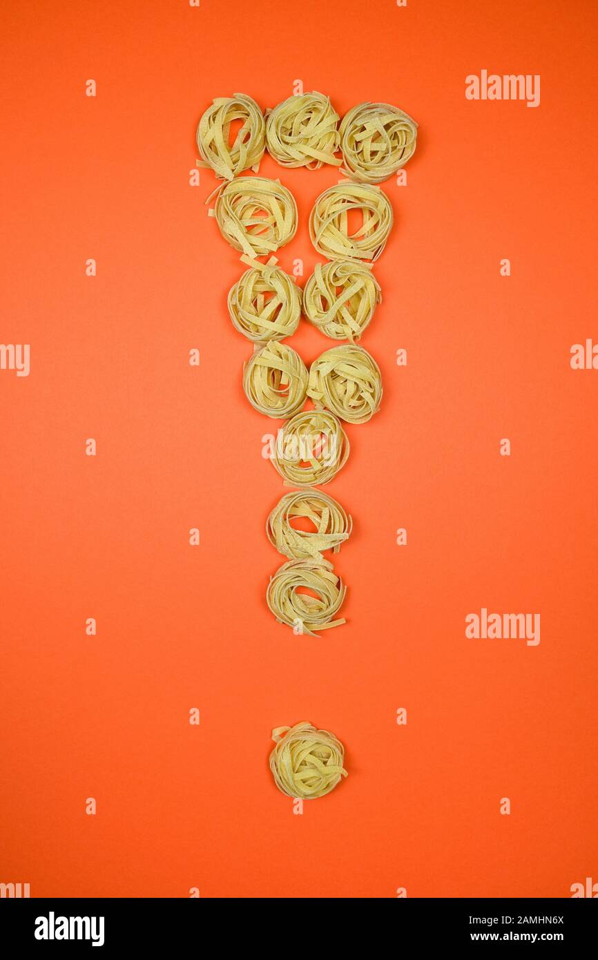 exclamation mark made from Italian tagliatelle pasta on red background ...