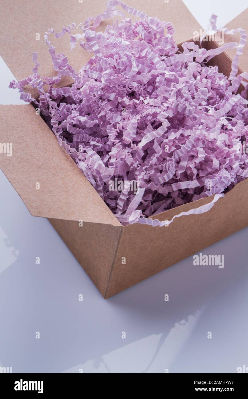 Opened cardboard box with purple decorative shredded paper Stock Photo ...