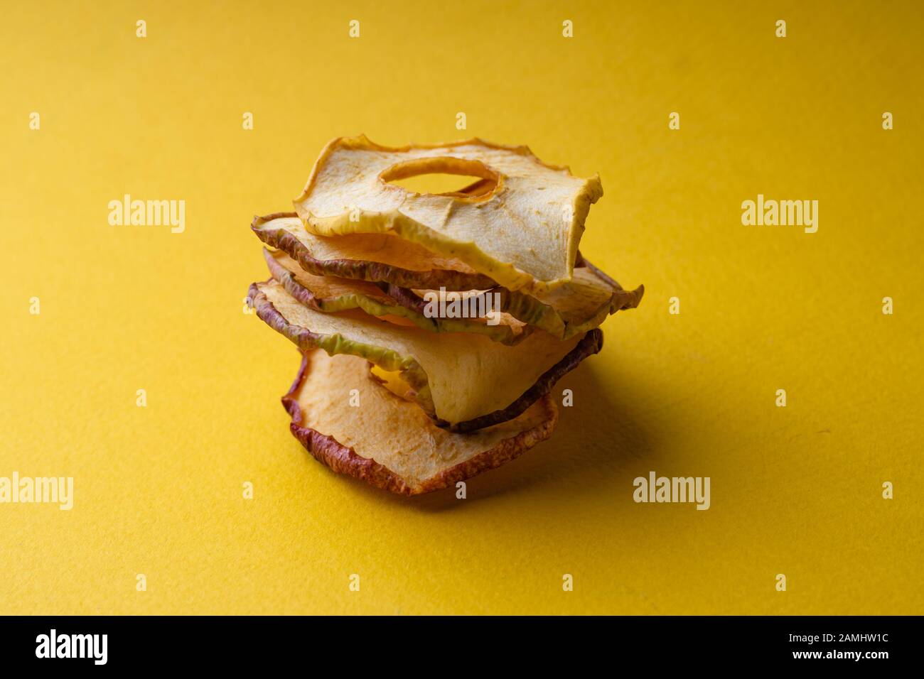 Pyramid of chips of dried apples on a yellow background and a place for ...