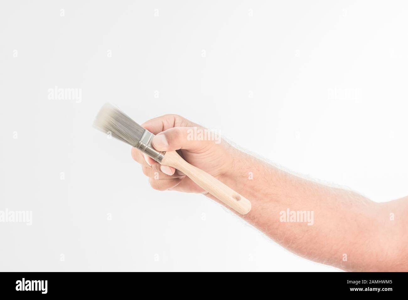 Close-up of a male arm and hand holding a paintbrush on its fingers on ...