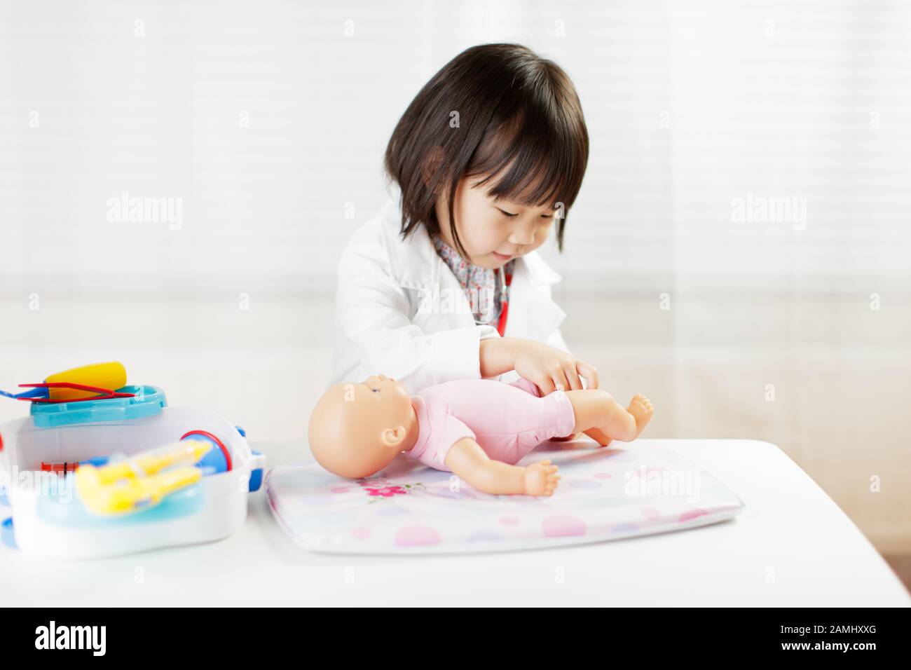 toddler girl pretend play doctor role at home against white background ...