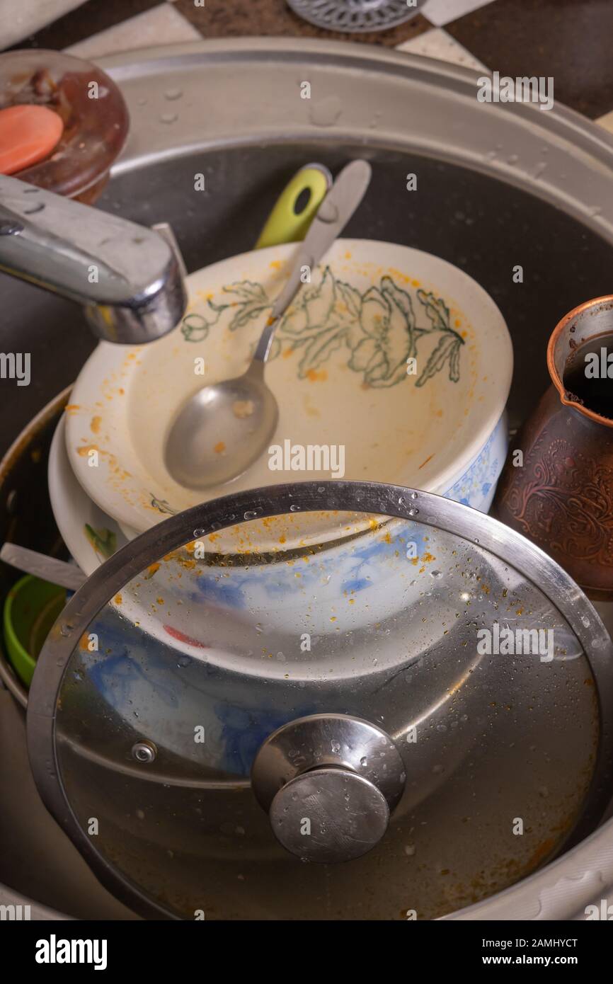 A mountain of unwashed utensils in a kitchen sink. Desolation and mess ...