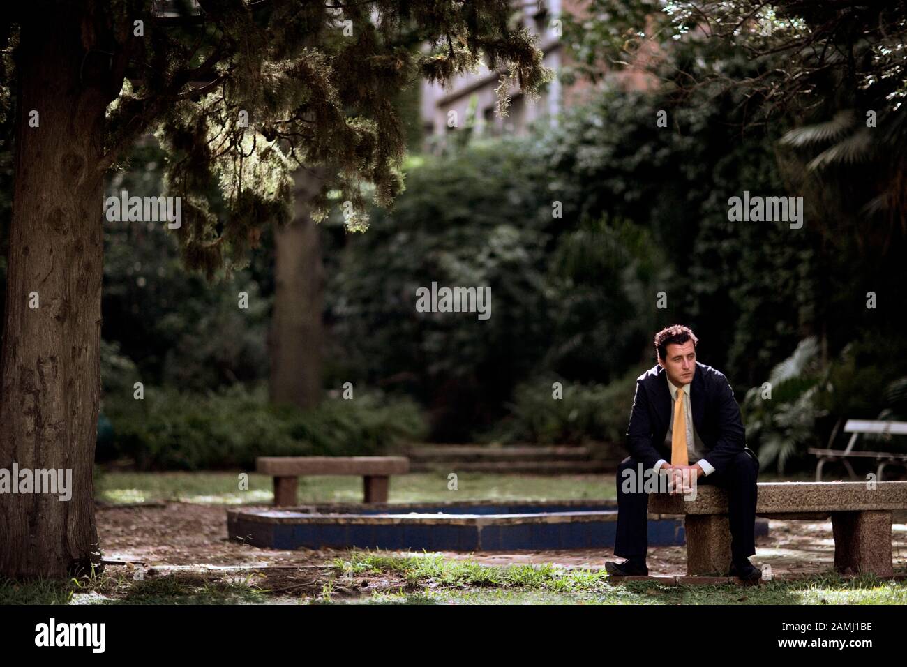 Front view of a man sitting alone on a park bench Stock Photo - Alamy