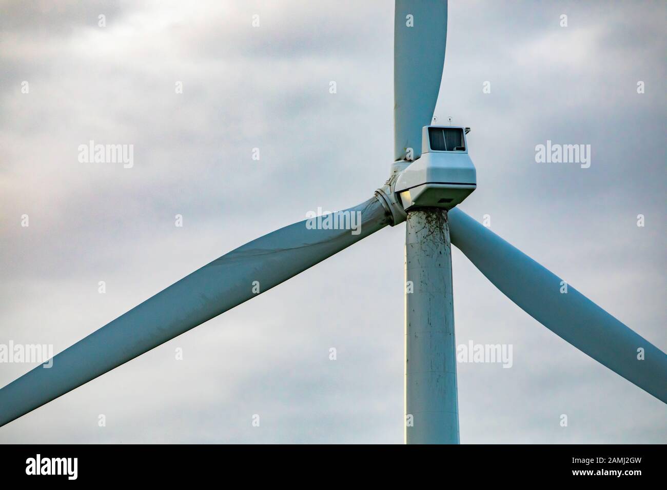 Closeup details of a wind energy converter tower against a grey cloudy ...