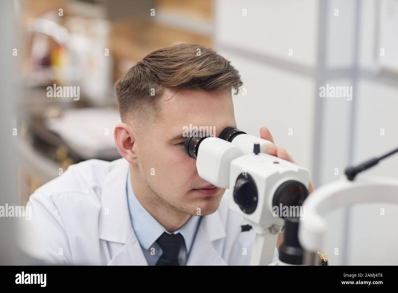 Closeup portrait of male optometrist using refractometer machine while ...