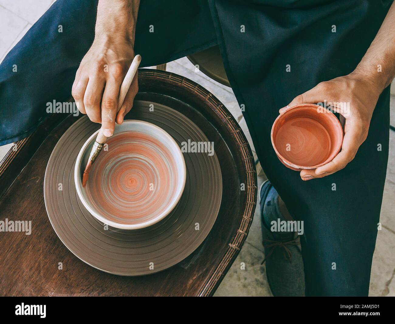 Ceramist at a pottery workshop Top view photo Man is glazing a ceramic ...