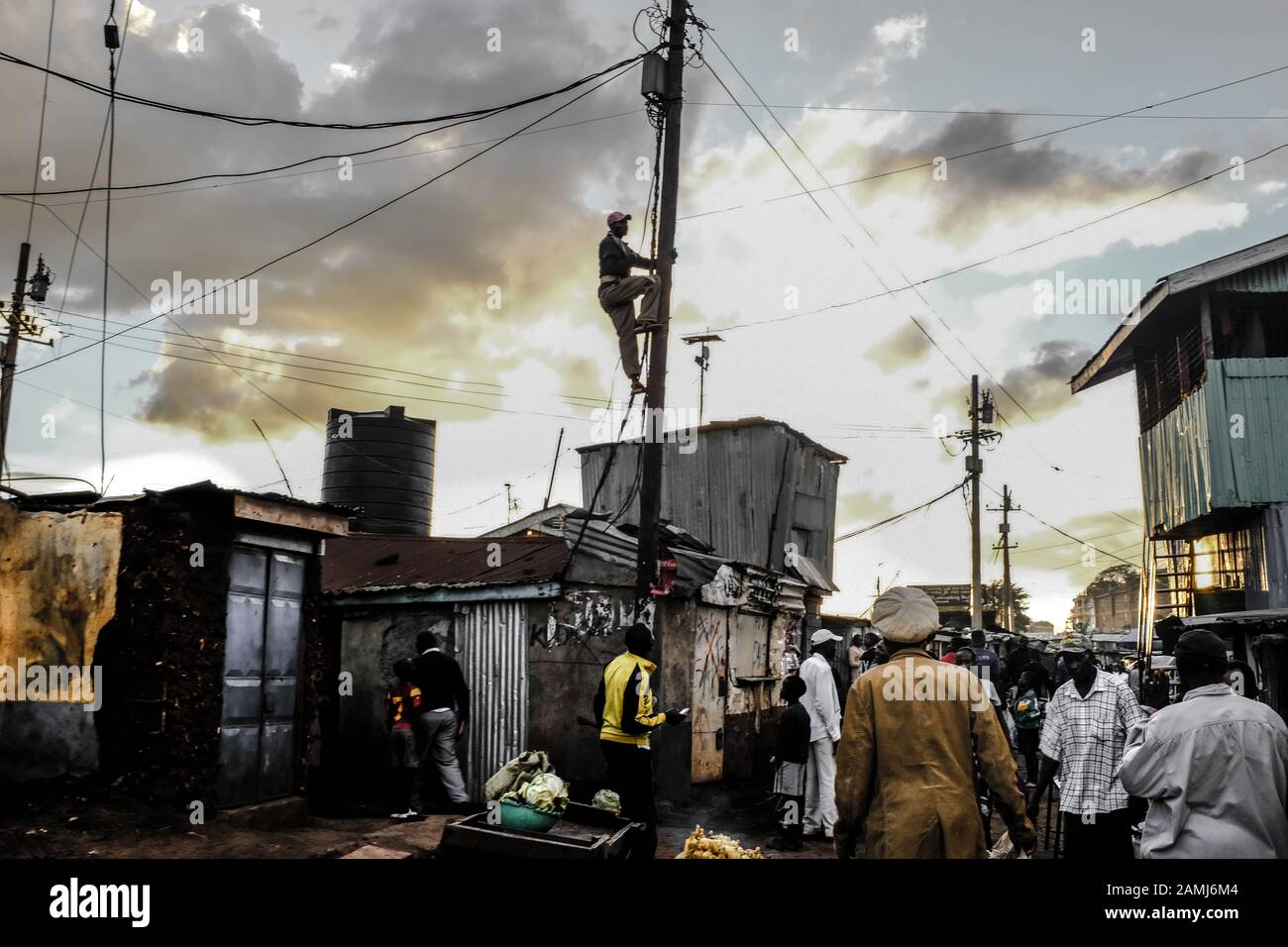 A local electrician climbs over an electric pole in Kibera Slums.Lack ...